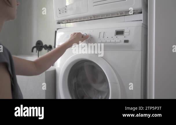 The woman turns on the home washing machine, selects a cycle for ...