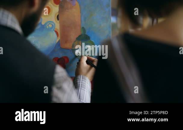 Back view of Skilled artist man teaching and showing young girl the ...