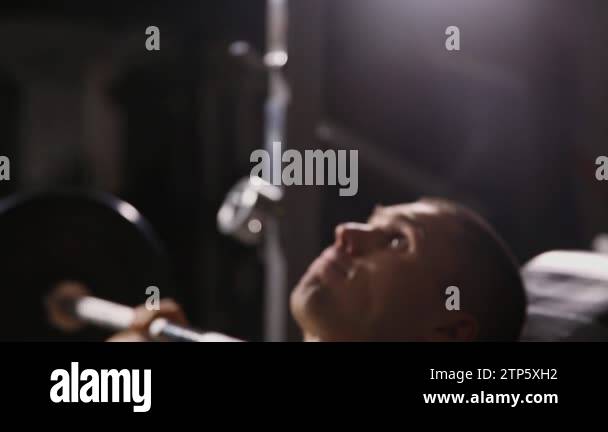 Inflated strong man with big muscles raises the bar lying on the bench ...