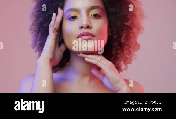 Biracial woman with dark curly hair in blue and pink light, slow motion ...