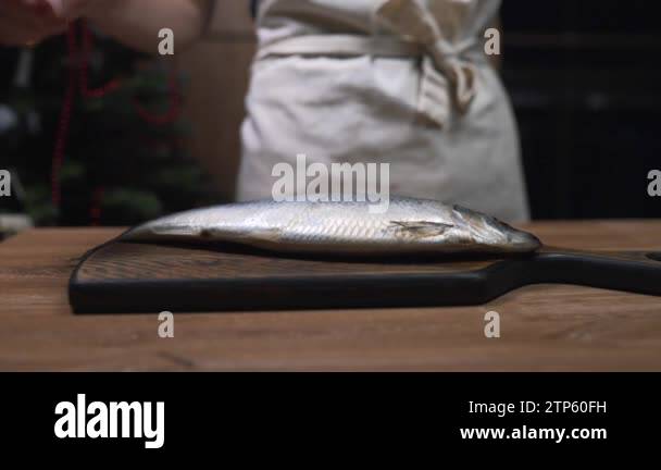 Chef puts herring fish to the wooden board and prepares for cooking ...
