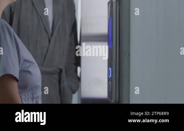 Close up shot of nurse in uniform coming to lift door, pressing call ...