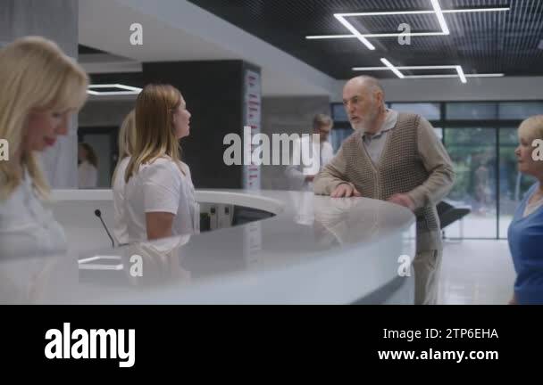Elderly couple come to reception desk in clinic lobby and make ...
