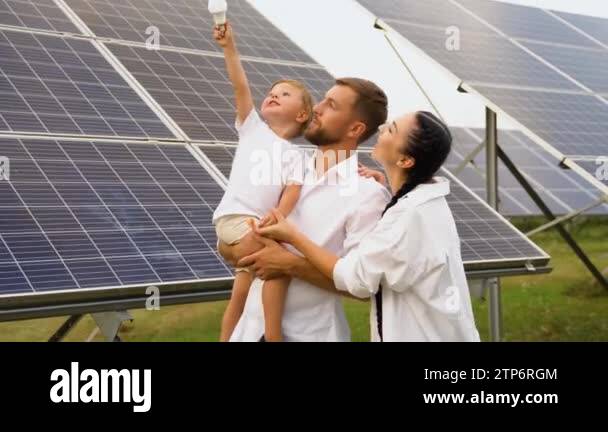 Family with light bulb near solar panels, showing the concept of green ...