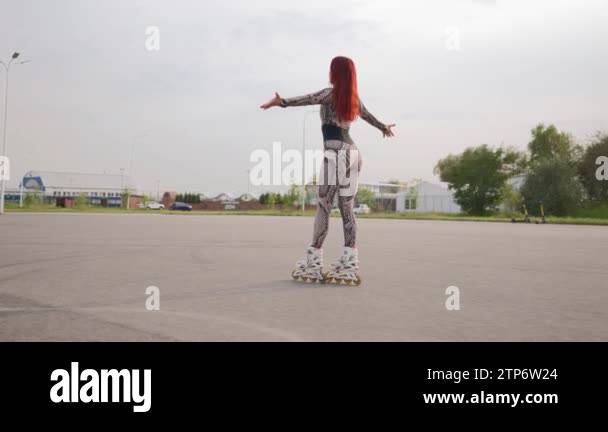 Slim Woman with Red Hair in Sports Overalls is Rollerblading. Beautiful ...