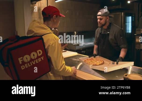 Medium shot of delivery service courier with bag walking into ...