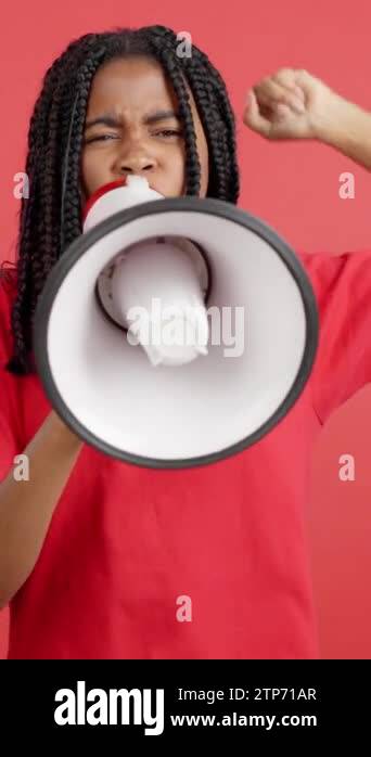 Upset african woman yelling using a loudspeaker in studio with red ...