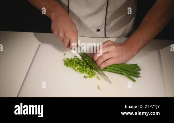 Cut the green onions with a knife on the board. Cutting green without ...