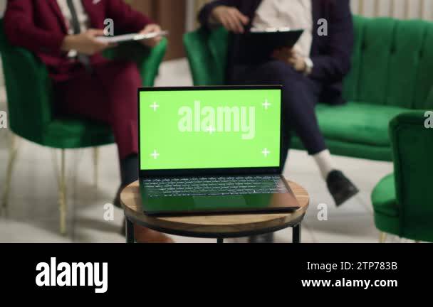 Greenscreen display on laptop in hotel lounge area, businessmen meeting ...