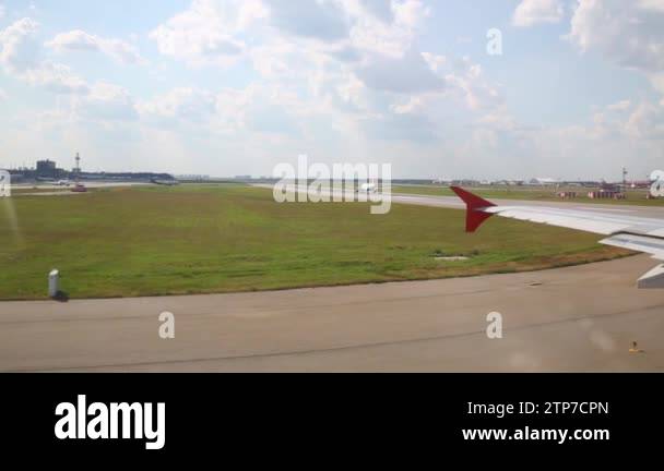 Wing of airplane moving by taxiway at airport through porthole from ...