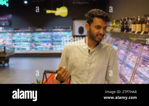 Indian man walking in aisle with his trolely at supermarket. Young man ...