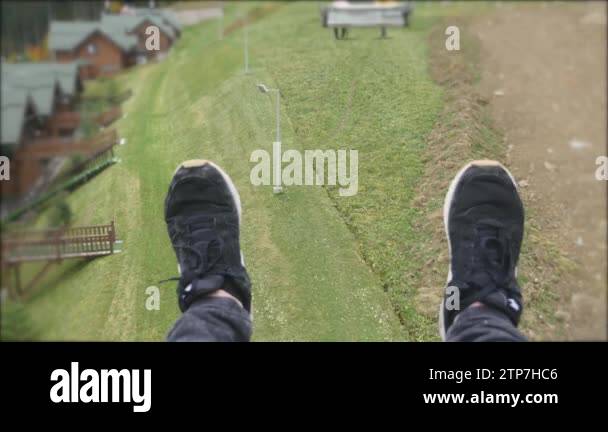 Ski-lift cable car leading. Top view on mans legs, green tree forest in ...