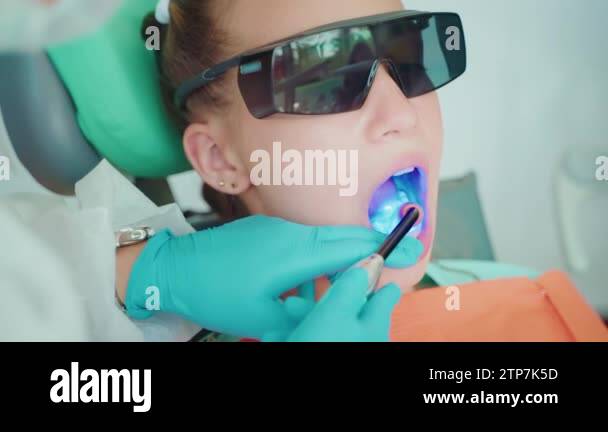 Dentist installs photopolymer seal in dentistry to patient teen girl ...