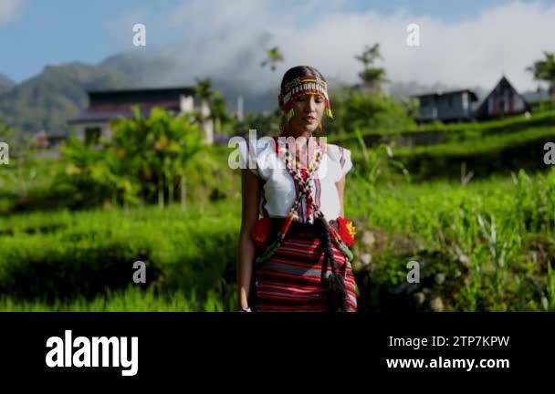 A woman clad in traditional Ifugao attire leisurely strolls, embracing ...