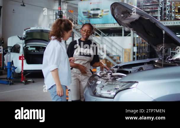 Certified repairman in auto repair shop showing customer what needs to ...