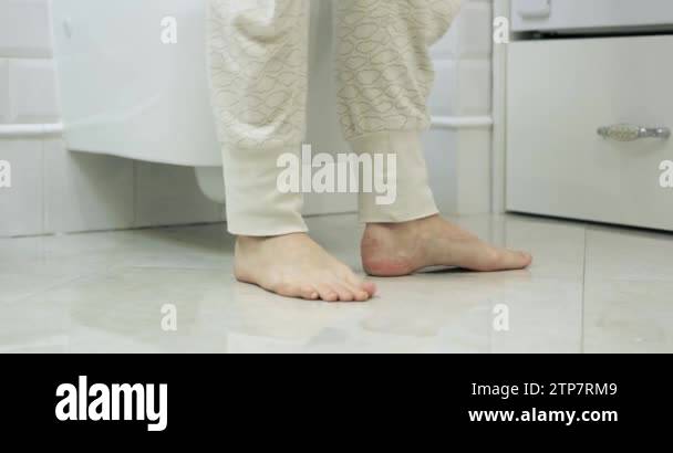 A woman enters the frame in casual pants, lowers them, and sits on the ...