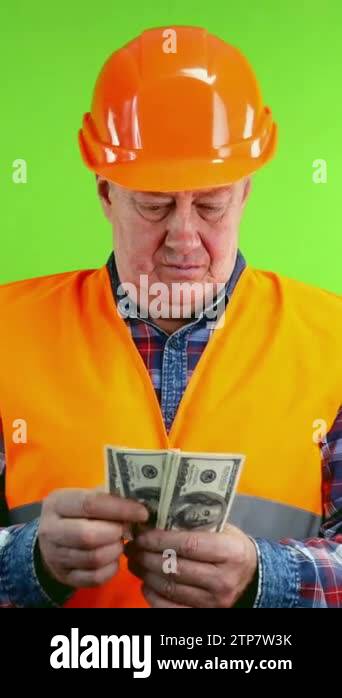 Senior builder in hardhat counts money from construction works and ...