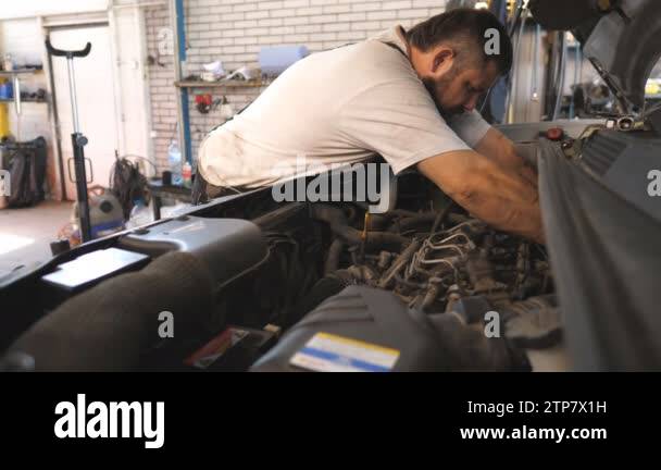 Repairman fixing engine of a car at workshop or service. Professional ...