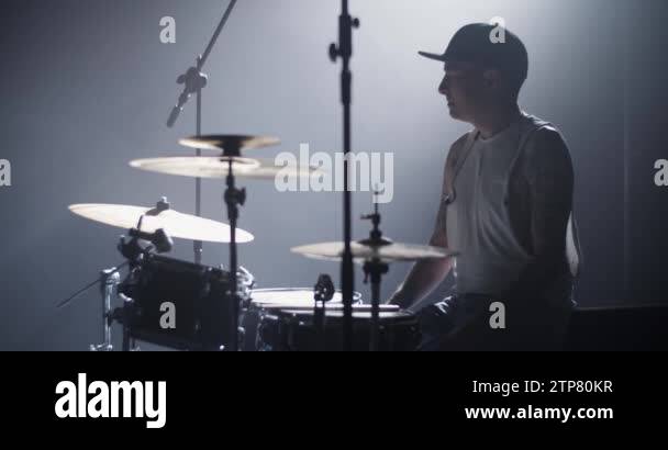 Male drummer putting on headphone in ear and spinning drumstick in hand ...