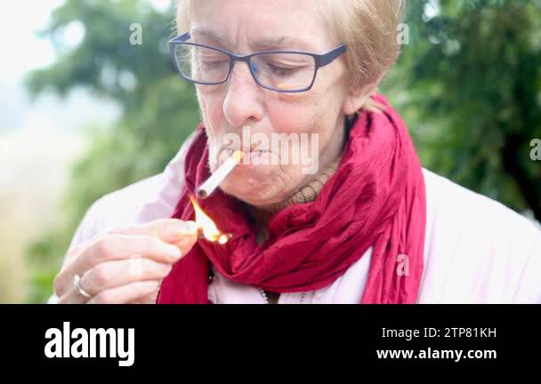 Cinemagraph of older woman standing outdoors and smoking a cigarette ...