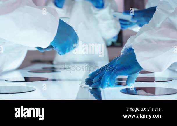 Scientific research team wearing full body suits examining hi-tech ...