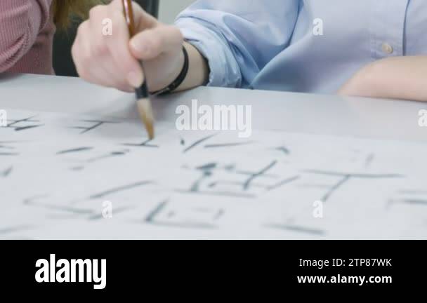 Woman teaching teen how to write Chinese characters at calligraphy ...