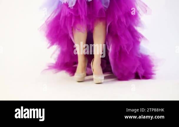 Woman on high heels and in a dress with a train goes from side to side ...