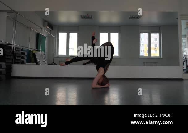 girl gymnast pulls leg to head arching in the back, stretching in ...