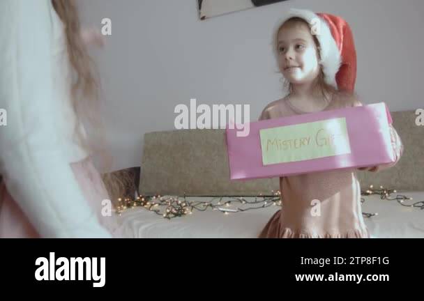 Happy little girl holding a mystery gift box. Another girl shows ...