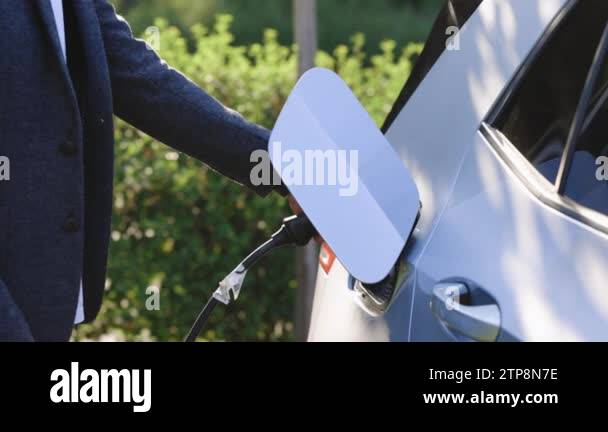 Unrecognizable businessman unplugging electric car. Luxury electrical ...