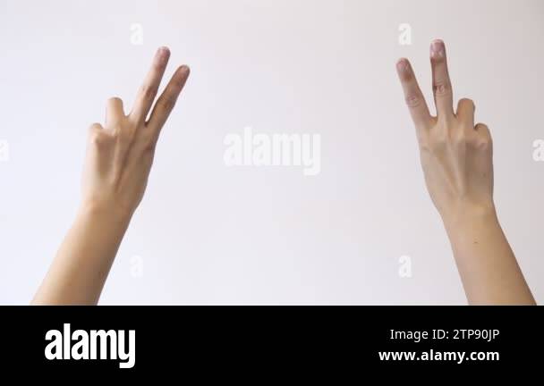 crossed fingers of a girl on a white studio background, hands showing a ...