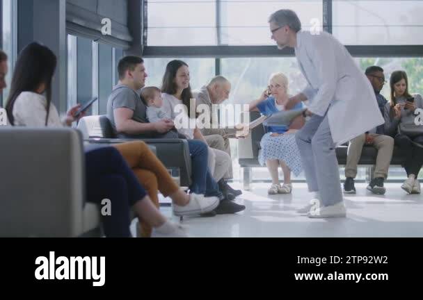 Diverse people sit on sofas in clinic lobby area, wait for doctors ...