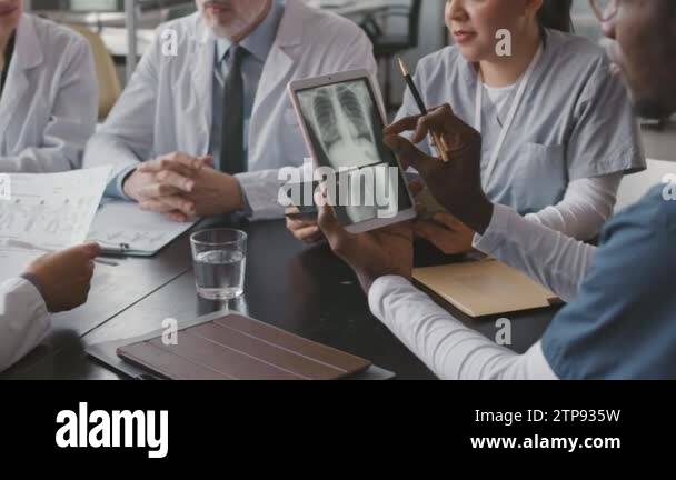 Diverse medical team analyzing patient chest x-ray on digital tablet ...
