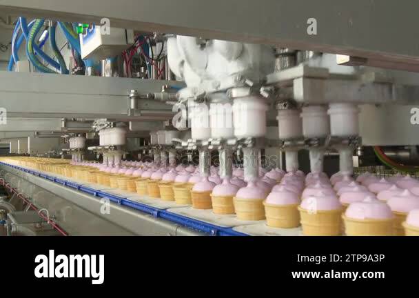 Ice cream factory. Filling of wafer cups with ice cream. Pink fruity ...