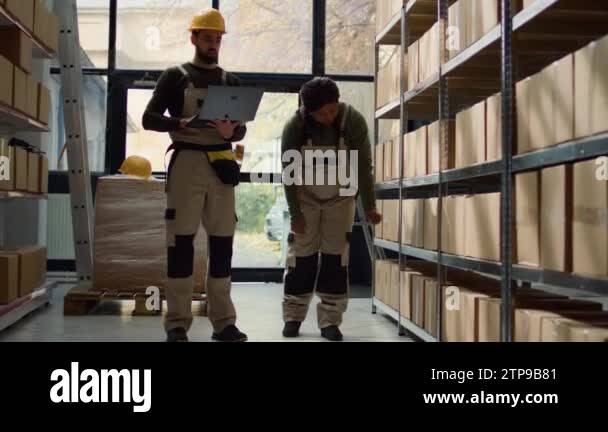 Employee and african american coworker walking through warehouse aisles ...