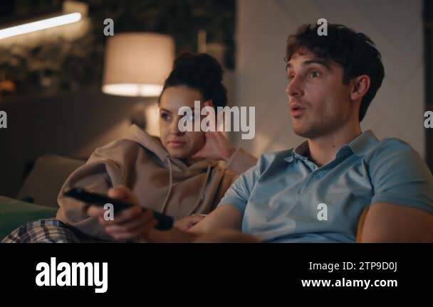Husband choosing tv channel sitting home couch with beautiful wife ...