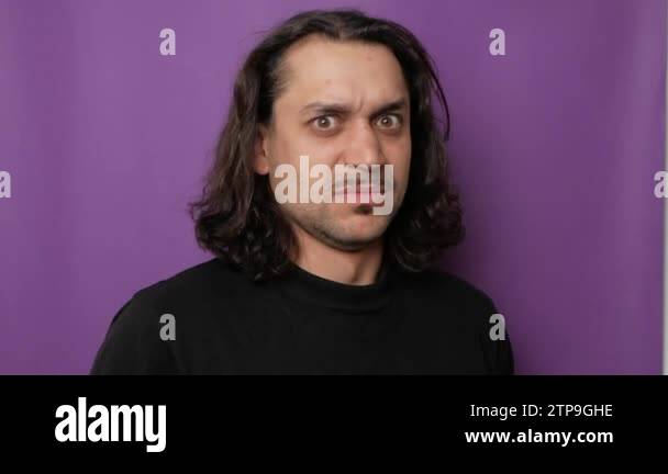 A funny, handsome guy shows indecent hand gestures. Portrait of a young ...