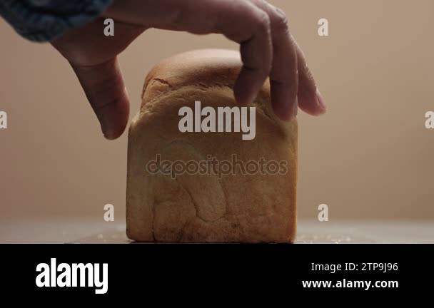 front view of brick of bread. Mans hand take off a front part of bread ...