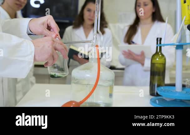 Concentrated female scientist conducting chemical experiment with ...