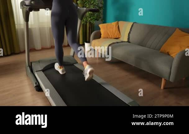Young woman doing her morning cardio exercise, running on a threadmill ...