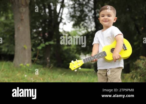 Handsome boy playing music in the park on the ukulele, the concept of ...