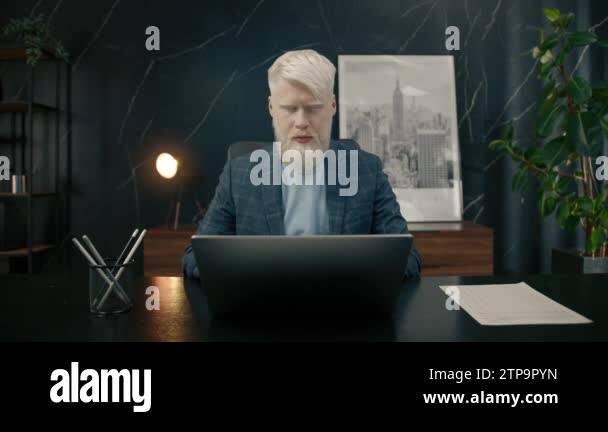 Focused albino entrepreneur typing on laptop at the desk. Male ...