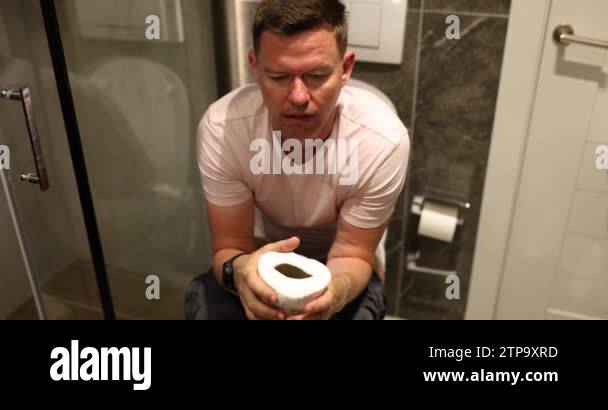Sad man sitting on toilet with intestinal problems. Constipation and ...