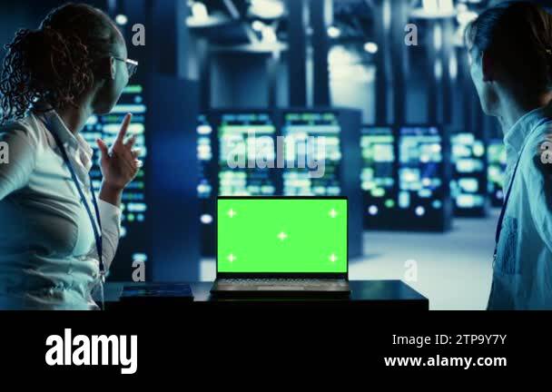 IT developers running code on green screen laptop, troubleshooting data ...