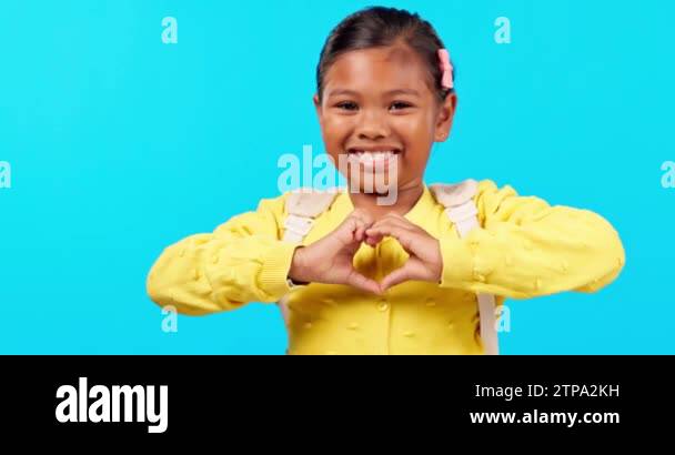 Portrait, girl with heart hand sign and against blue background with ...