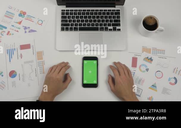 Businessman using smartphone with green screen at white office table ...