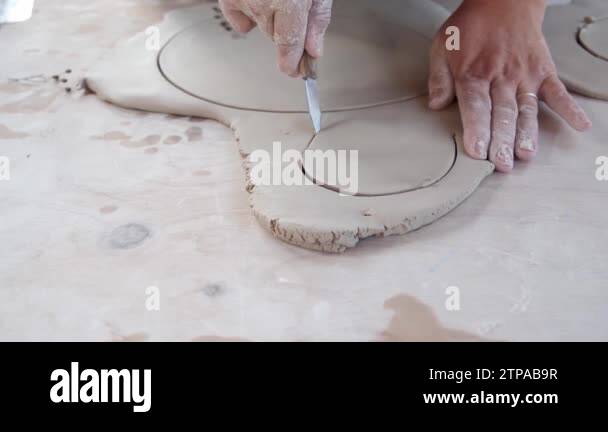 Crop unrecognizable artist with knife cutting out circles from clay ...