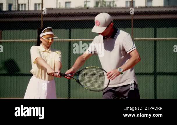 A man tennis coach teaches his ward to hold the racket correctly and ...