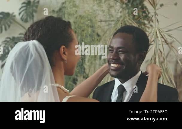 Back view chest up of young Biracial bride adjusting black suit of her ...