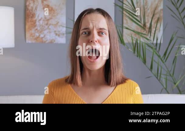 Frustrated young screaming woman covering ears with pillow feeling ...